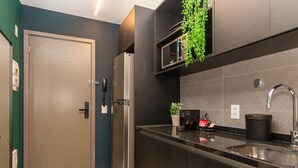 Uma cozinha moderna com armários escuros, uma geladeira de aço inoxidável, micro-ondas e pia com torneira.