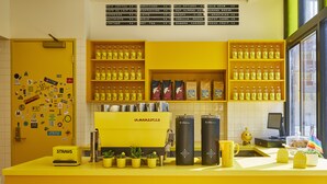 Bancada amarela de café com um quadro de menu acima, exibindo diversas opções de café e comida.