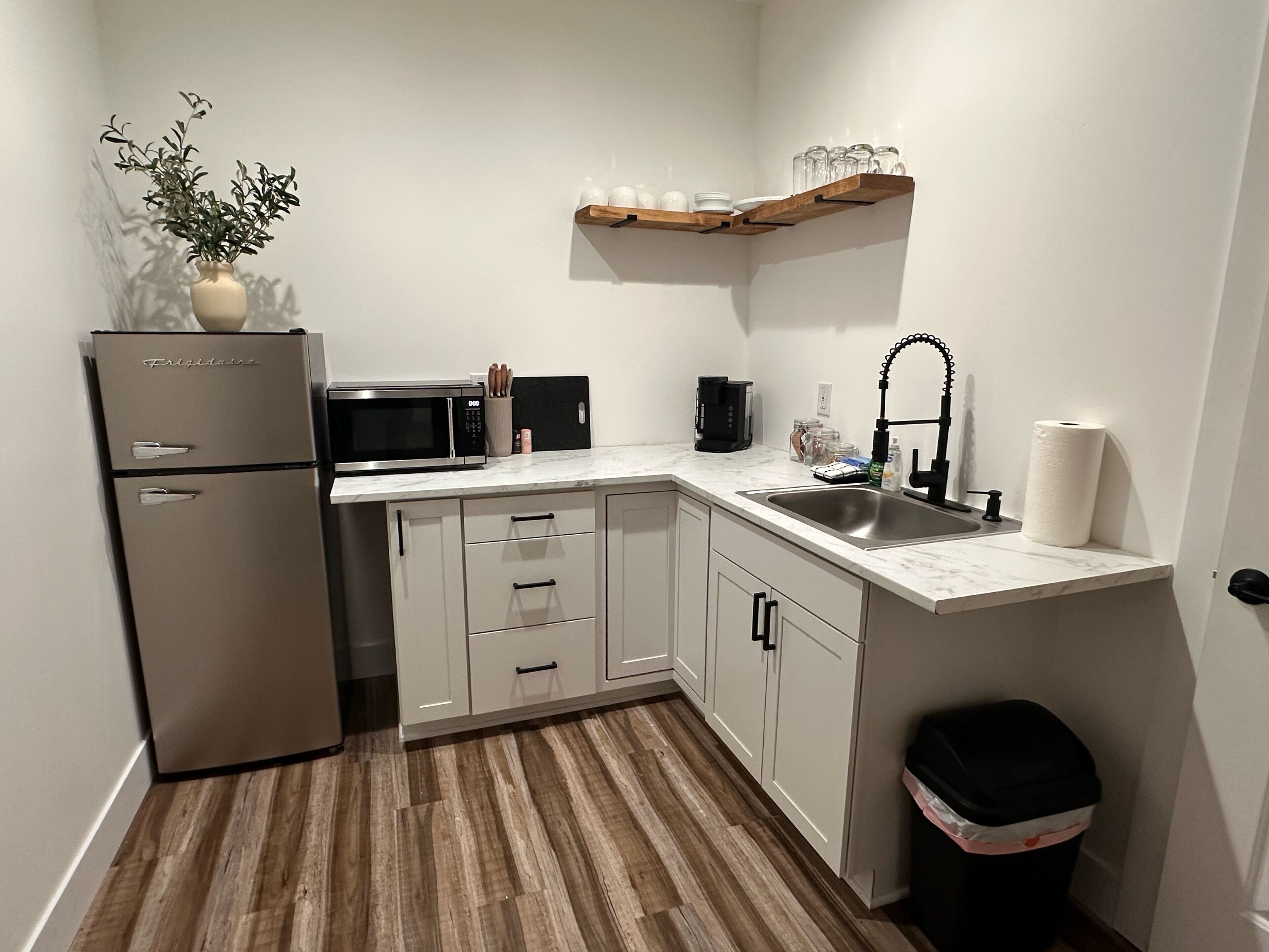 Cozinha compacta com geladeira, micro-ondas, pia e um pequeno balcão.