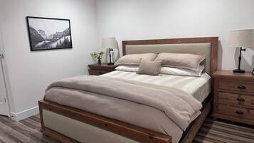 Uma cama bem arrumada com cabeceira de madeira, uma mesa de cabeceira com abajur e um quadro na parede.