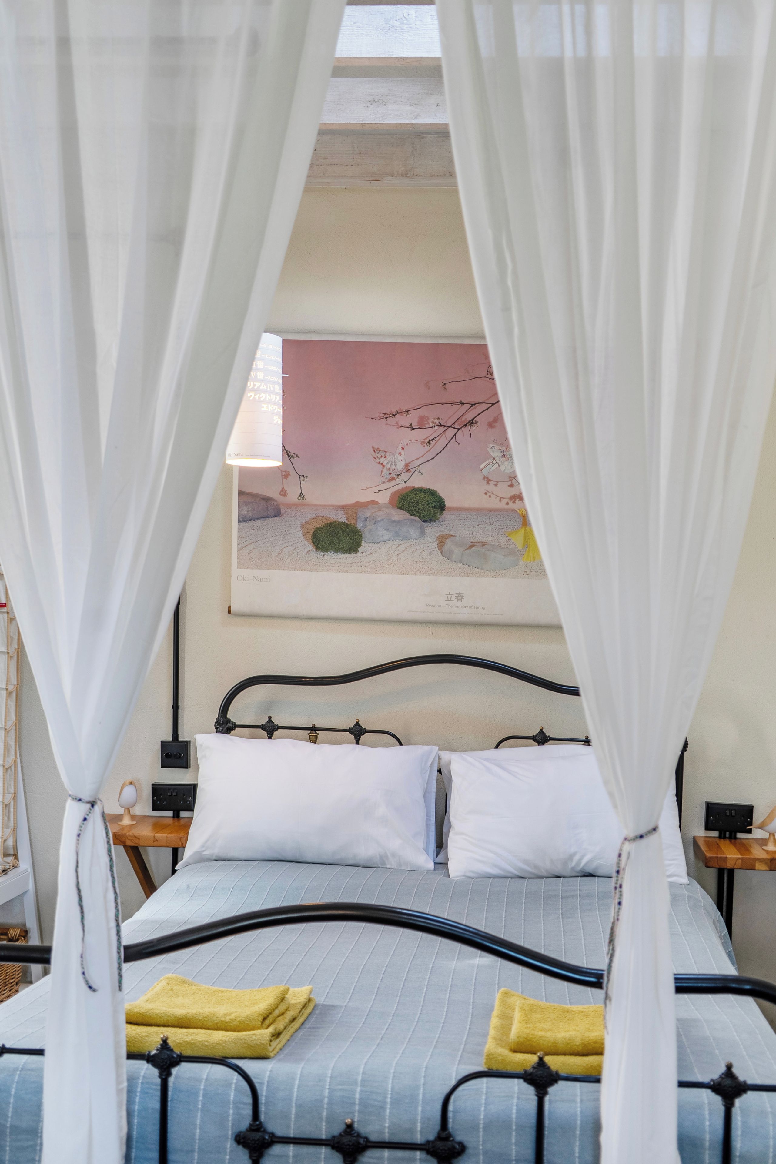 Uma cama com dossel, almofadas e mesa de cabeceira com abajur.
