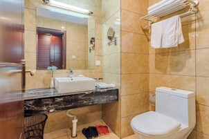 Casa de banho com bancada de mármore, sanita, lavatório, espelho e porta-toalhas.