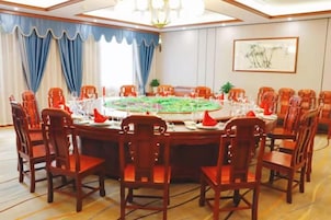 Sala de conferência com mesa redonda, cadeiras e lustre.