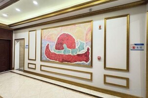 Um corredor com uma grande obra de arte abstrata na parede, uma porta e um sinal indicando área proibida para fumantes.
