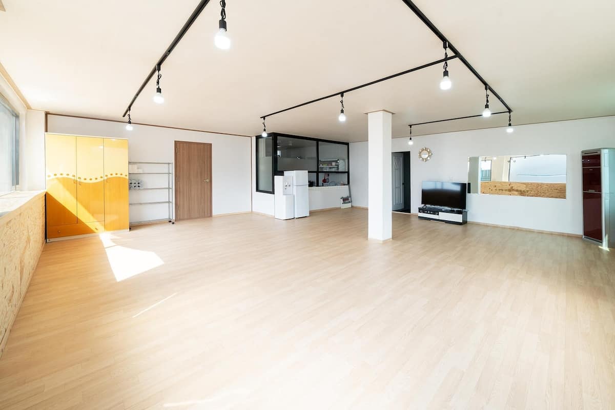Uma sala de estar ampla com cozinha, área de refeições e uma grande janela que oferece iluminação natural.