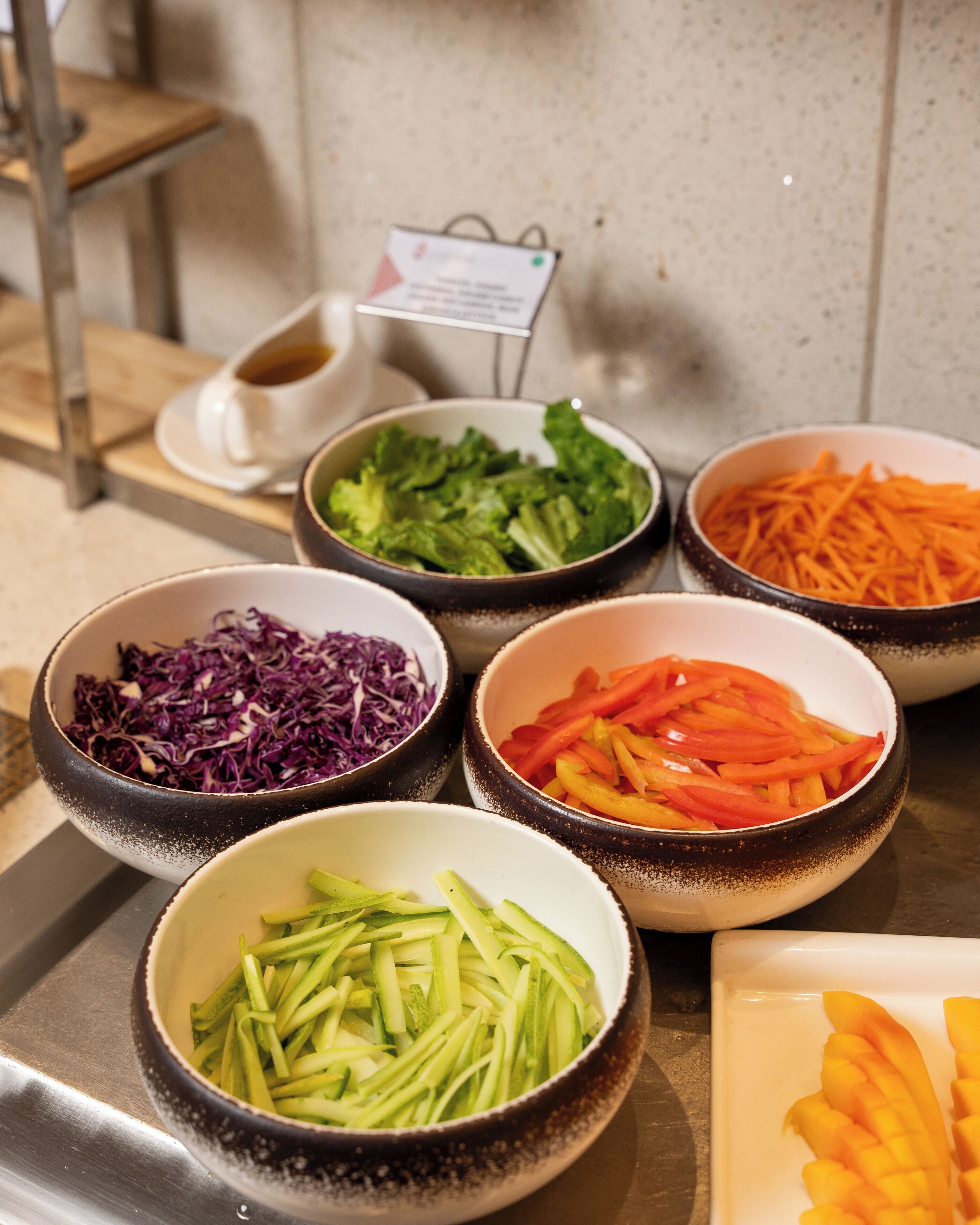 Buffet com diversas tigelas de legumes fatiados.
