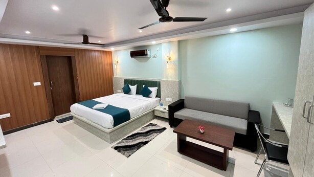Quarto de hotel moderno com cama, sofá e pequena mesa de jantar.