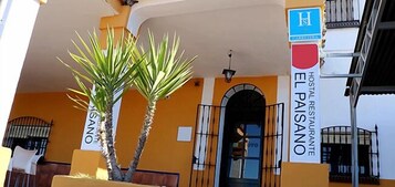 Um edifício com uma placa indicando 'EL PASANO HOSTAL RESTAURANTE'.