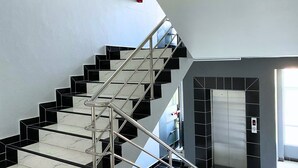 Escadaria moderna com degraus de mármore preto e branco e corrimão de metal.