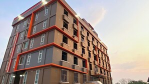 Um edifício com vários andares e design arquitetônico moderno, com varandas e grandes janelas.