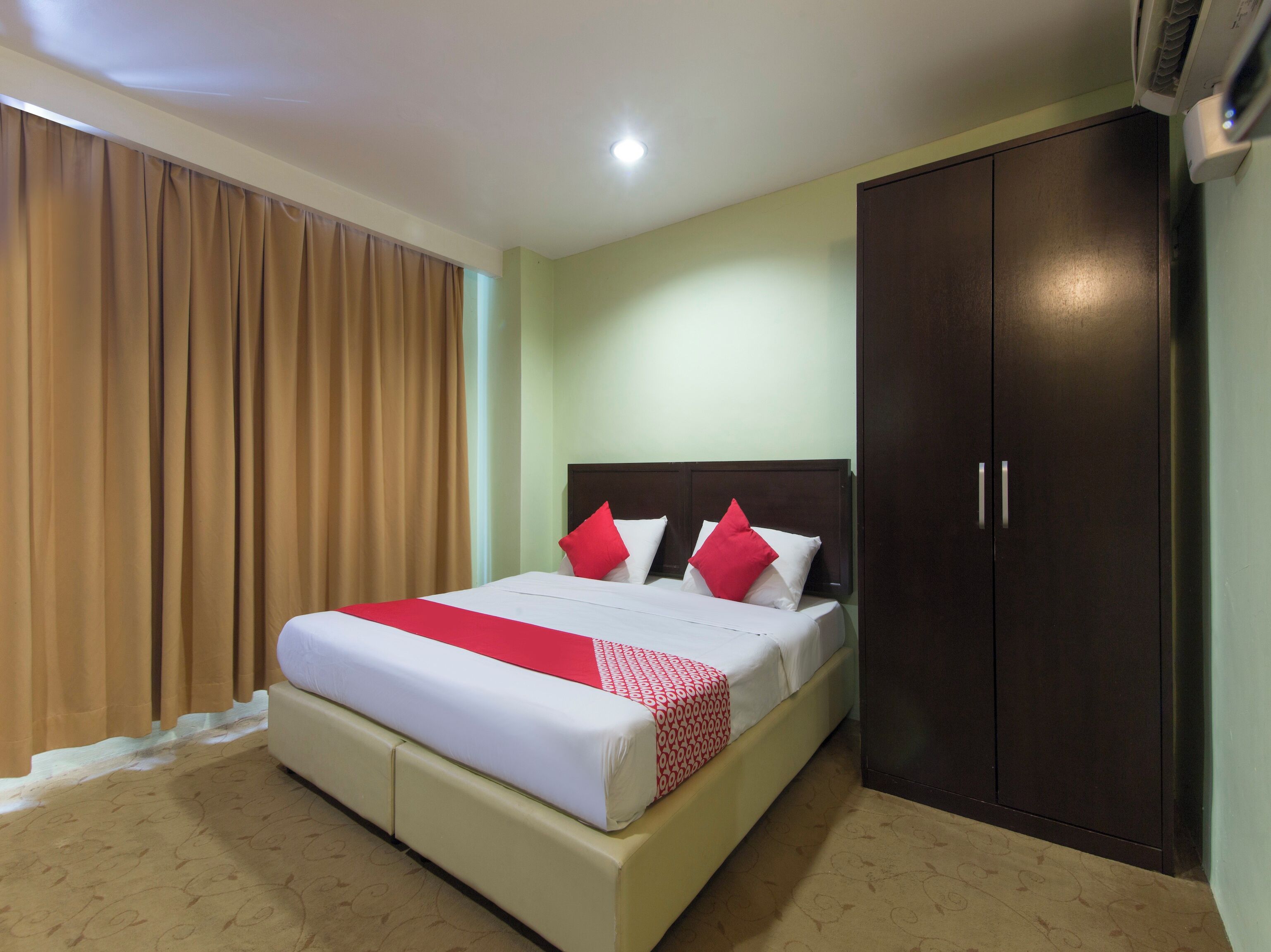 Quarto de hotel com uma cama, um guarda-roupa e uma janela com cortinas.