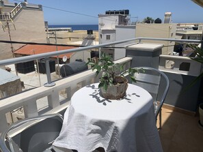 Varanda com mesa, cadeiras e um vaso de planta.