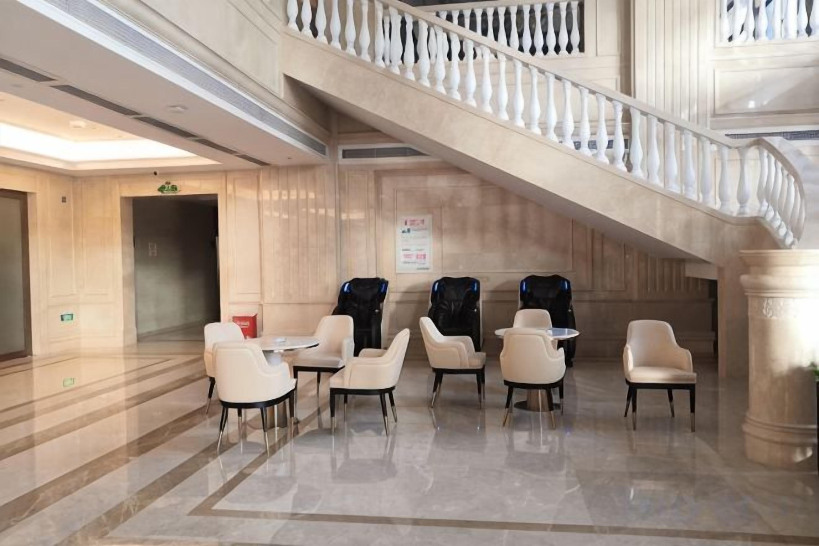 Um saguão de hotel com piso de mármore, uma escadaria e várias áreas de estar.