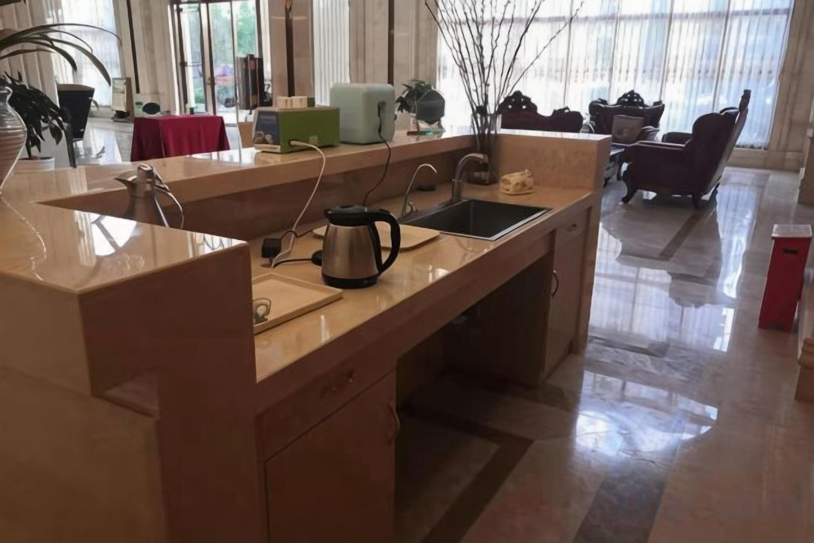 Cozinha com pia, bancada e chaleira. Área de refeições com cadeiras e mesa ao fundo.