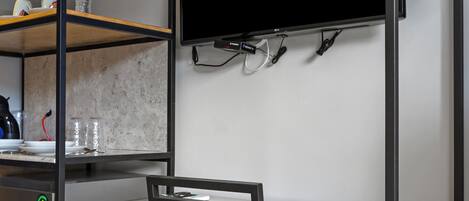 Uma cozinha compacta moderna com televisão integrada, uma cadeira e um armário estante.