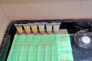 Um espaço de armazenamento com várias embalagens verdes e brancas, algumas com etiquetas amarelas, e um recipiente de plástico transparente com tampa branca.