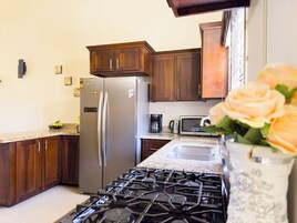 Uma cozinha moderna com armários de madeira escura, eletrodomésticos de aço inoxidável e bancada de granito.