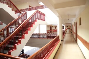 Interior com vários níveis, uma escadaria central, diversos andares e um corredor longo.