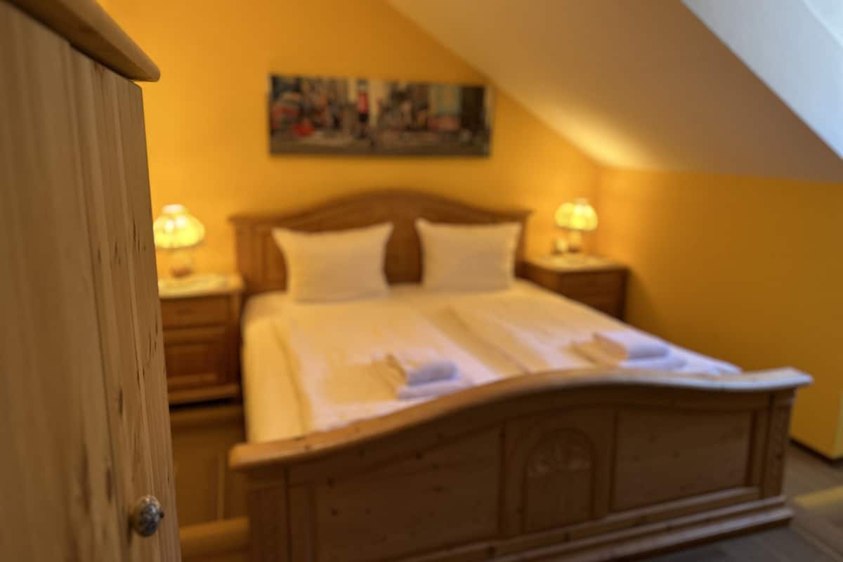 Quarto com cama de madeira, duas luminárias de cabeceira e um quadro na parede.