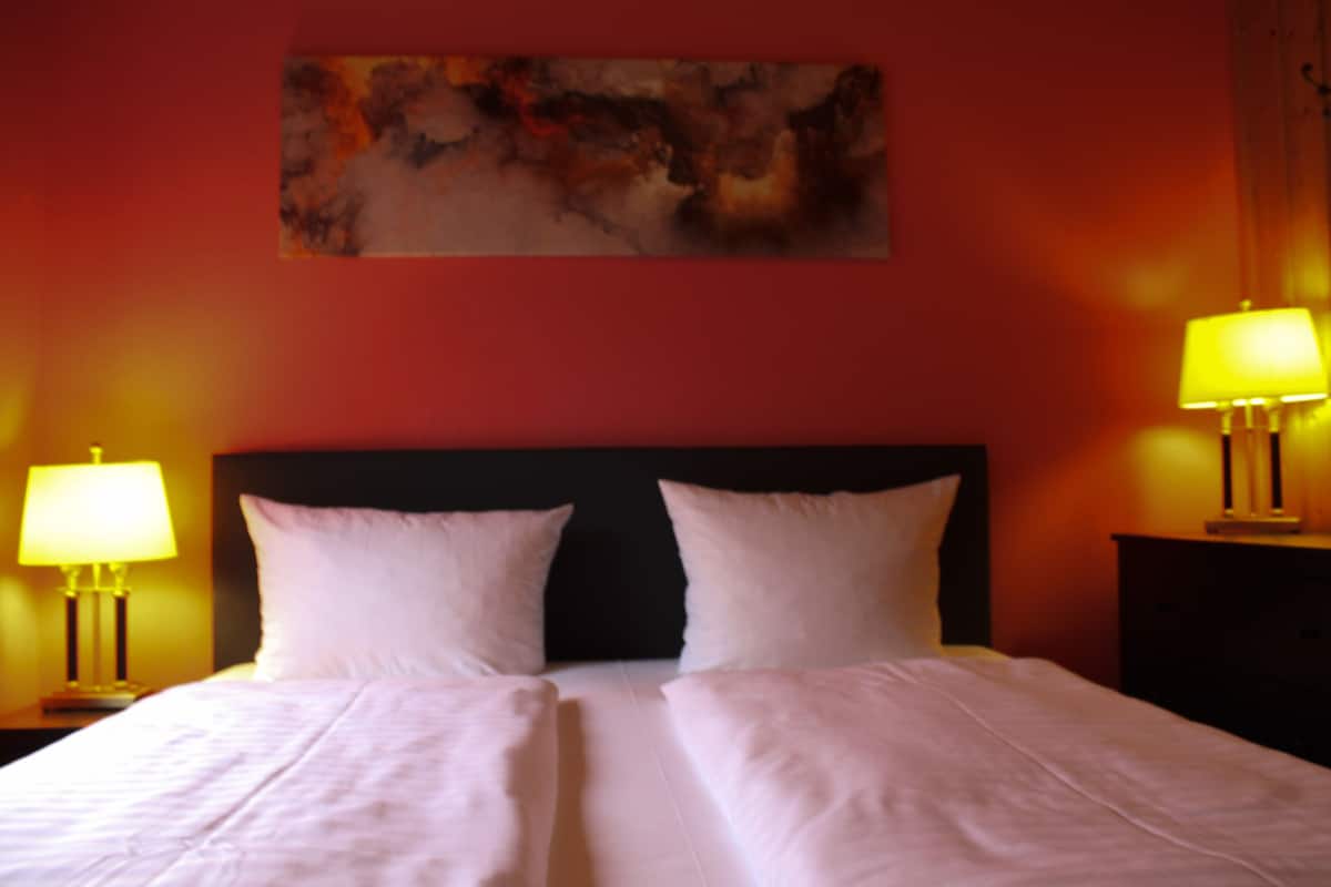 Quarto de hotel com uma cama grande, duas luminárias de cabeceira e um quadro na parede.