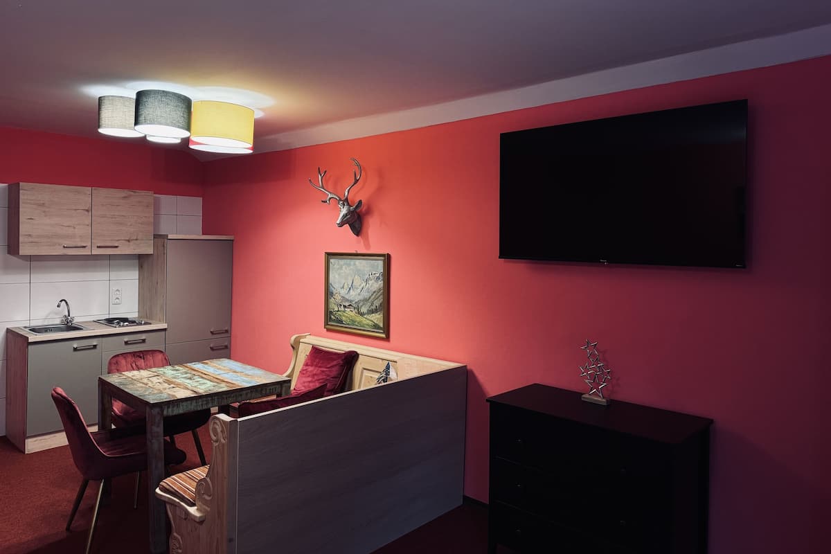 Quarto compacto com cozinha compacta, área de refeições e TV na parede.