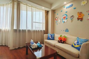 Sala de estar com sofá, mesa de centro e janela com cortinas.