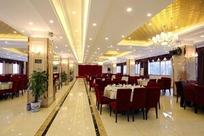 Um restaurante espaçoso com várias mesas e cadeiras, piso lustroso e um candelabro.