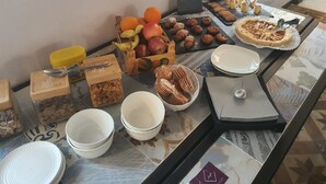 Uma mesa de buffet com diversos alimentos, incluindo frutas, doces e um bolo.