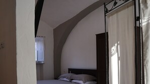 Quarto com cama, janela com cortina e piso de azulejos.