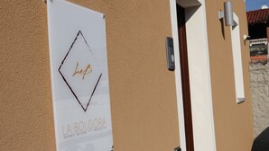 Placa para 'La Bolgora Guest House' com um design geométrico simples e uma assinatura manuscrita.