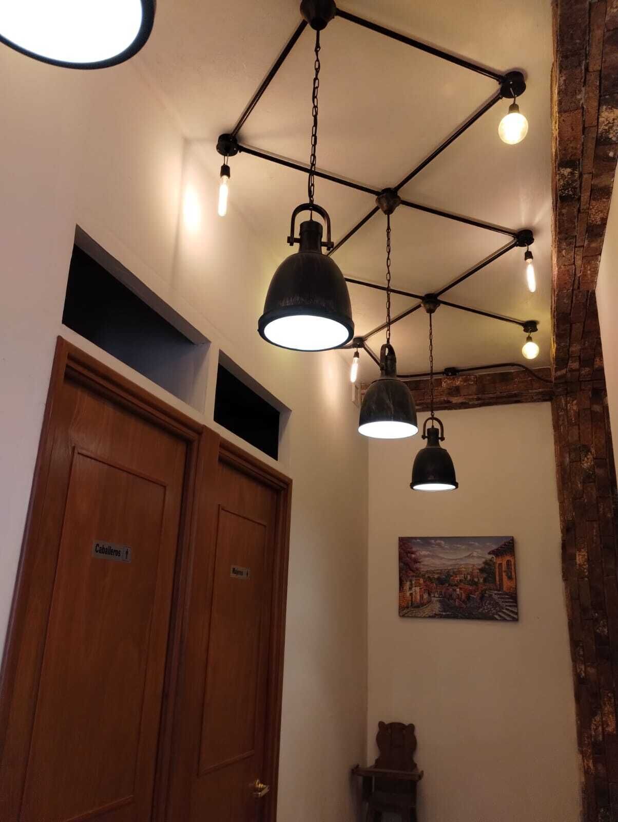 Teto com várias luminárias pendentes, portas de madeira e um quadro na parede.