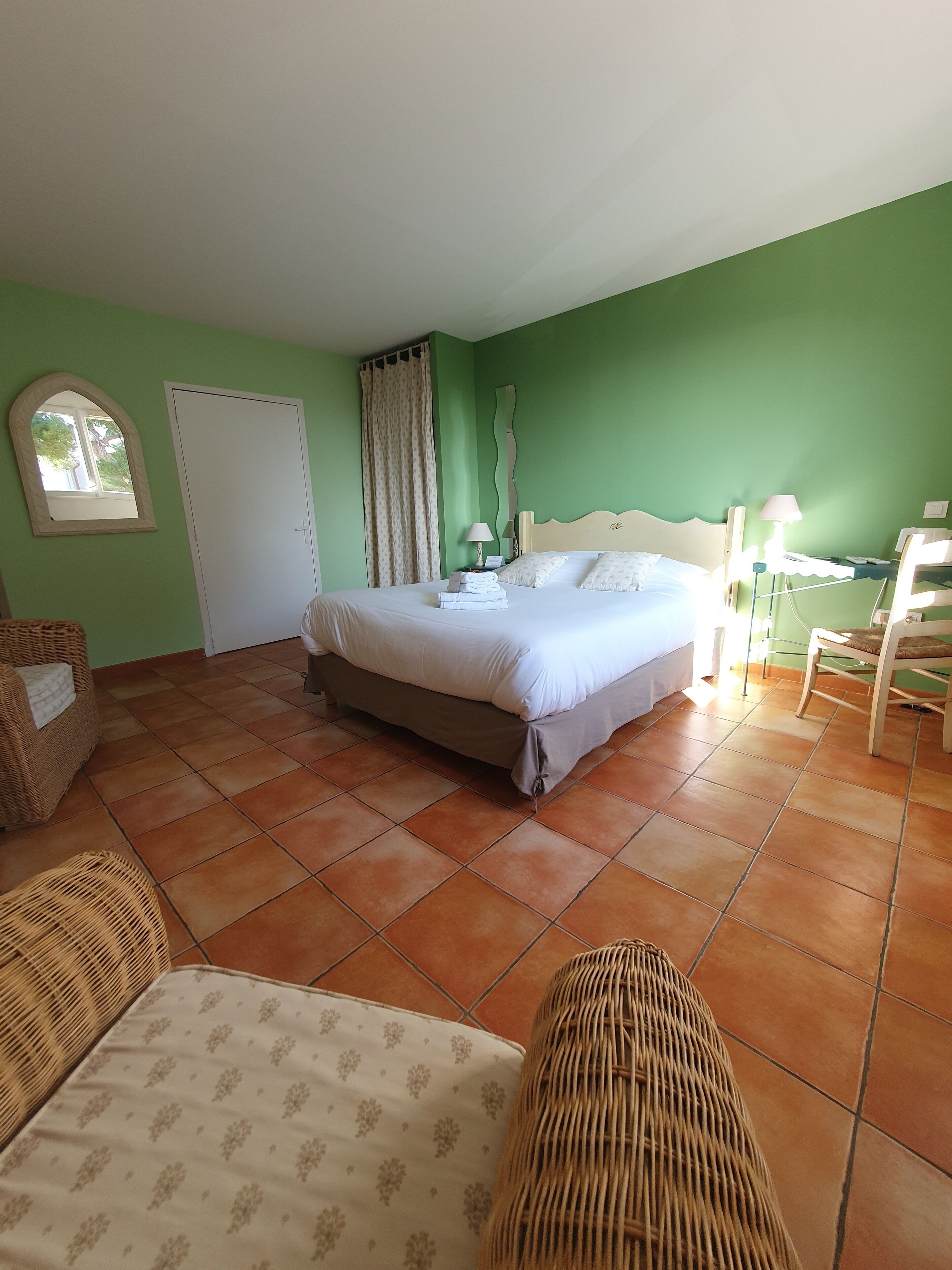 Um quarto com uma cama, uma cadeira, uma mesa e um espelho.