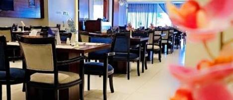 Um saguão de hotel com um balcão de recepção extenso, diversas áreas de estar e um design de teto colorido.