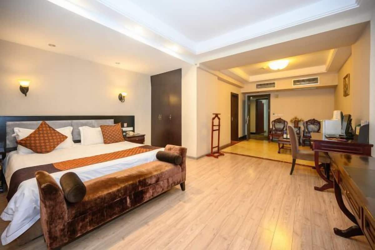 Quarto de hotel com uma cama grande, uma escrivaninha e uma cadeira.