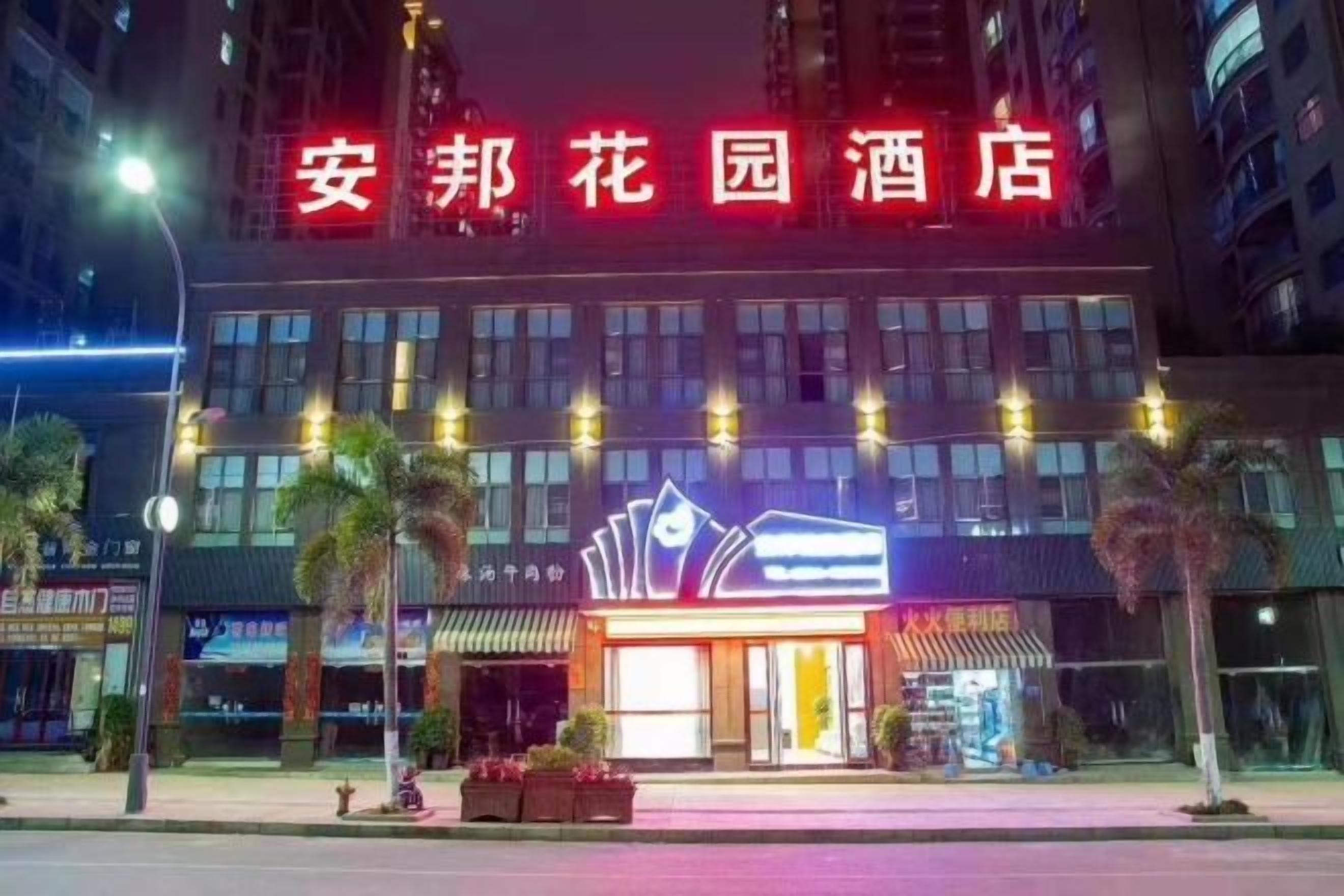 Um hotel com uma placa vermelha chamativa, vários andares e uma entrada bem iluminada.