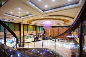 Um espaço interno com uma escadaria curva, um lustre central e piso polido.