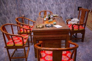 Uma mesa de jantar de madeira com cadeiras, um bule, xícaras e um cardápio.