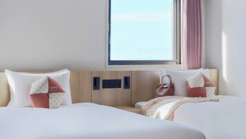 Quarto de hotel com duas camas, cada uma com travesseiro ostentando um logotipo e texto, uma janela com vista e um painel de controle na parede.