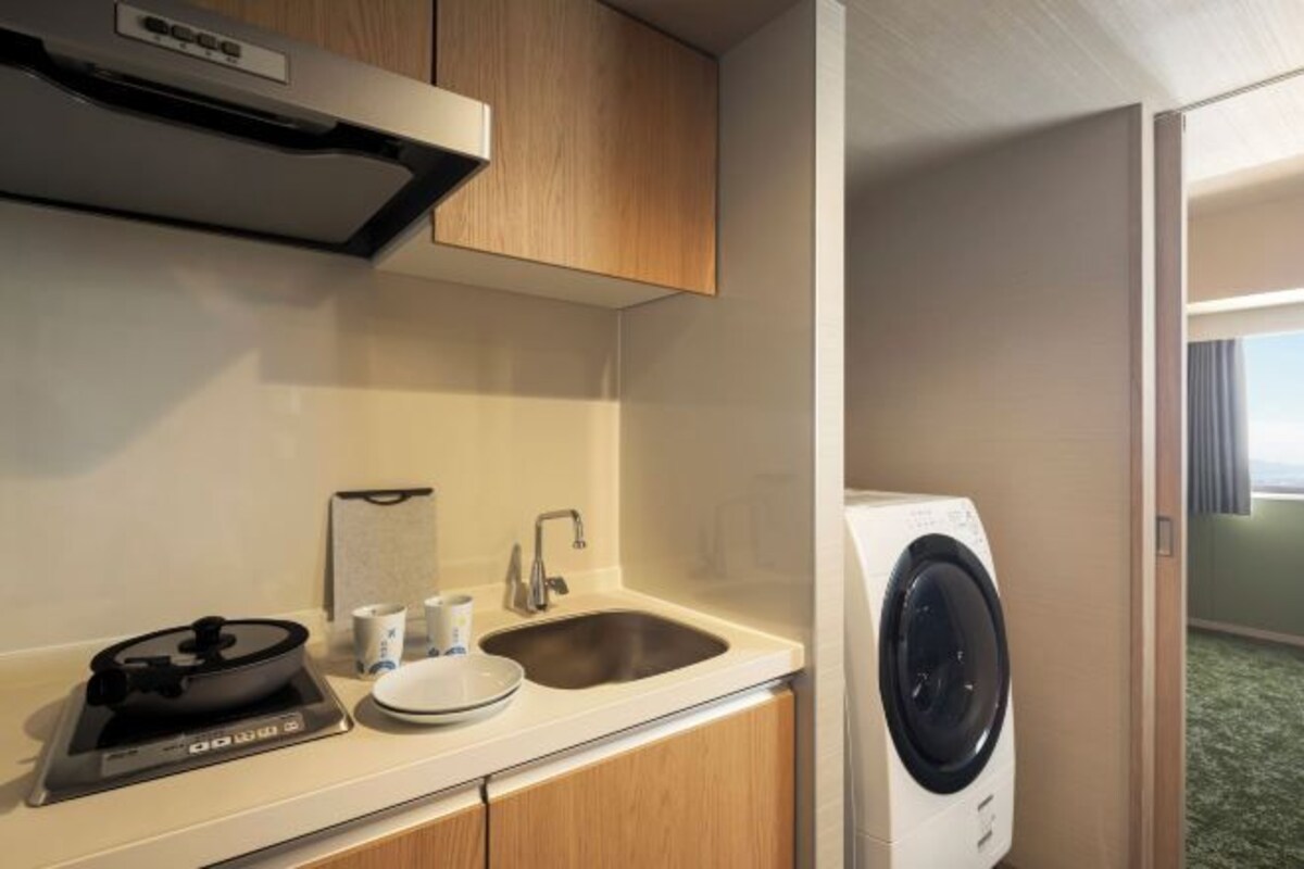 Uma cozinha compacta equipada com micro-ondas, pia e máquina de lavar.