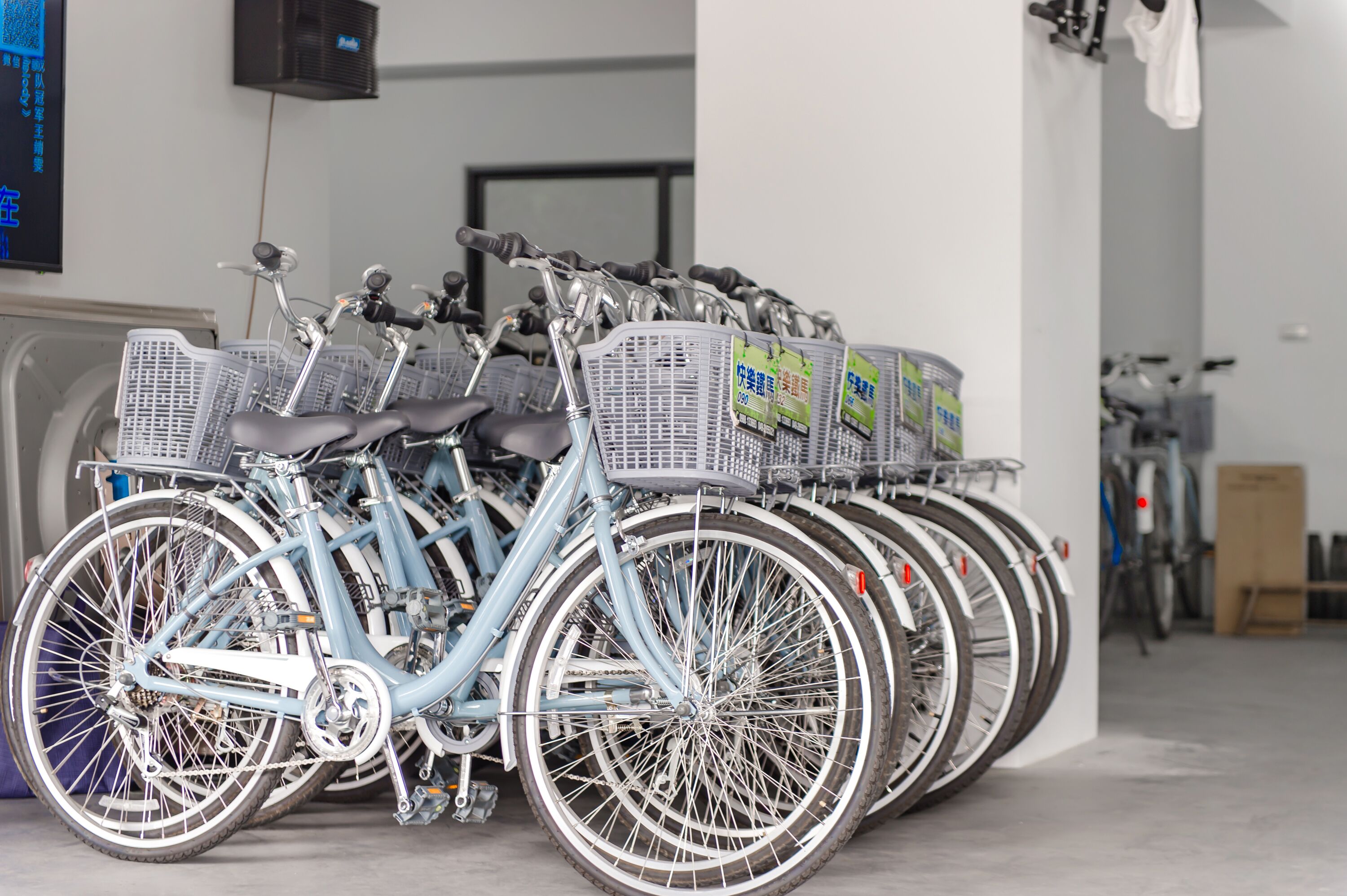 Uma fileira de bicicletas com cestas, estacionadas em ambiente interno.