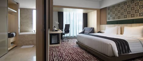 Quarto de hotel com uma cama grande, uma escrivaninha, uma cadeira e um banheiro.