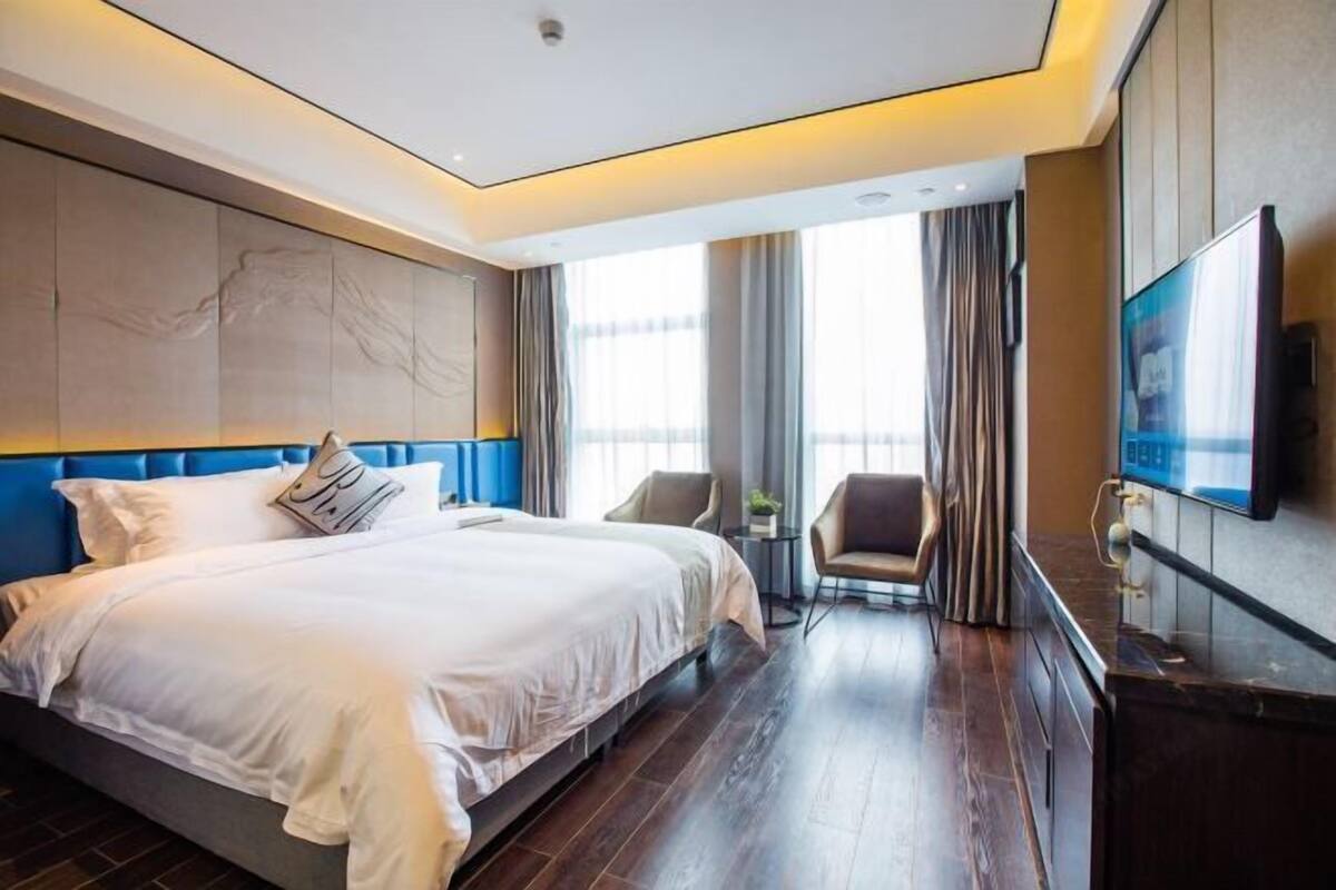 Quarto de hotel com uma cama grande, televisão, mesa pequena e uma cadeira.