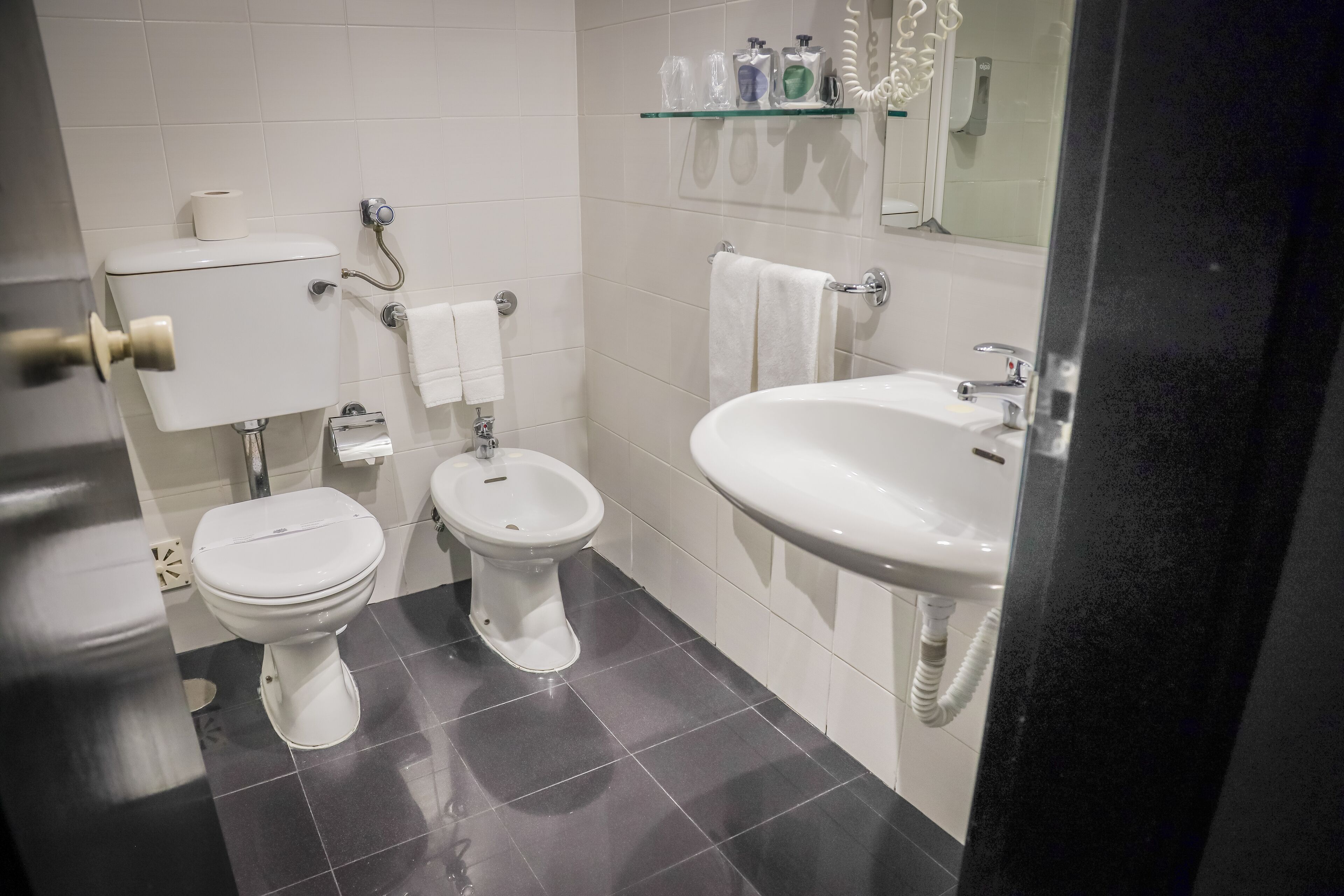 Uma casa de banho moderna com sanita, bidé e lavatório.