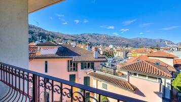 Uma varanda com vista para uma cidade, edifícios com telhados de terracota e uma montanha ao fundo.