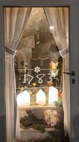 Uma porta com painel de vidro exibindo uma decoração com lápides e uma pequena estátua.