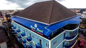 Hotel com fachada azul e telhado marrom, com varandas e várias janelas.
