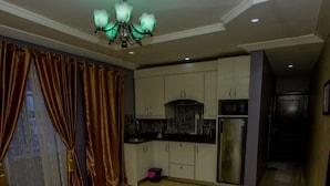 Uma sala de estar com sofá, mesa de centro e uma área de cozinha com armários e eletrodomésticos.