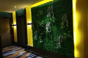 Um corredor com parede verde, tapete estampado e porta à esquerda.