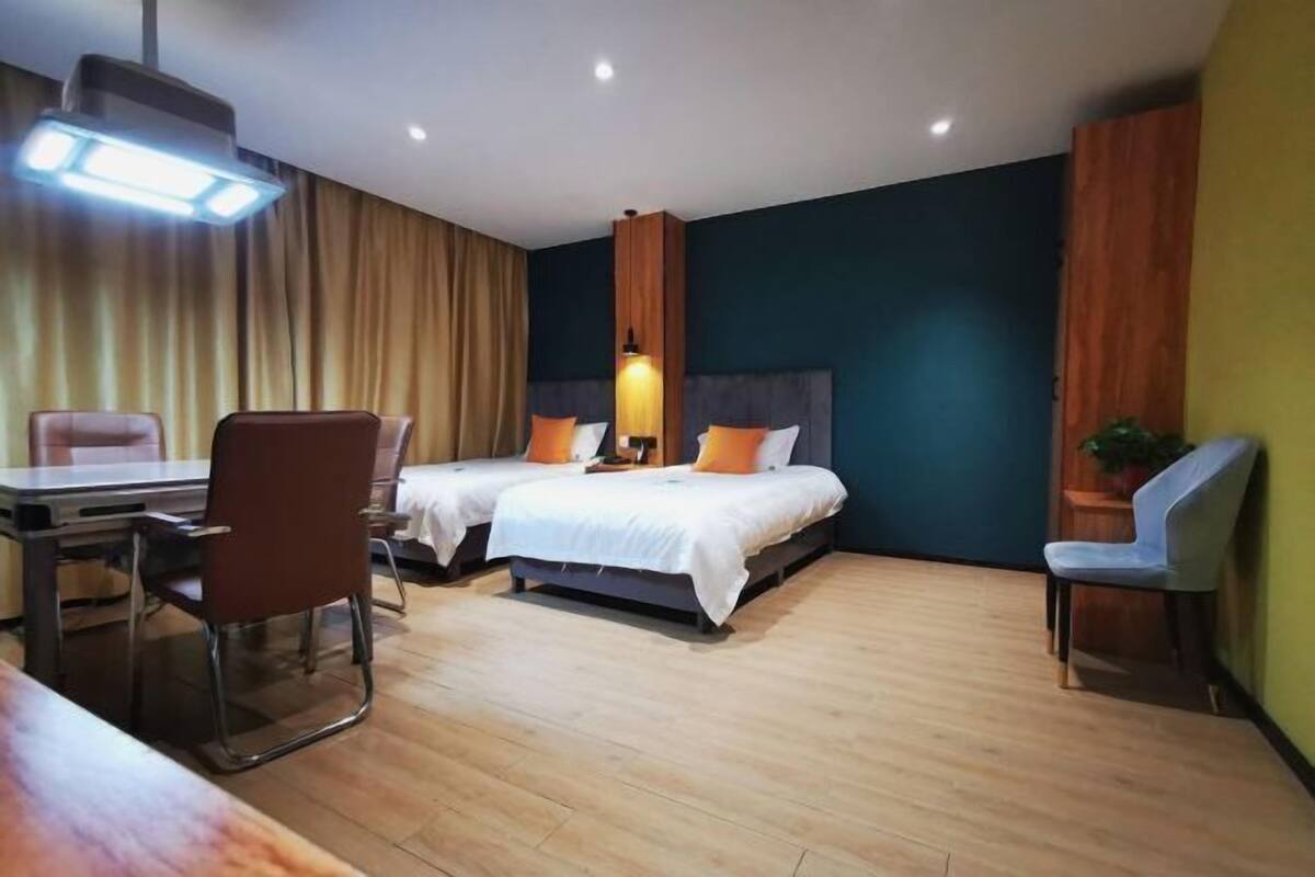 Quarto de hotel com duas camas, uma escrivaninha e uma cadeira.