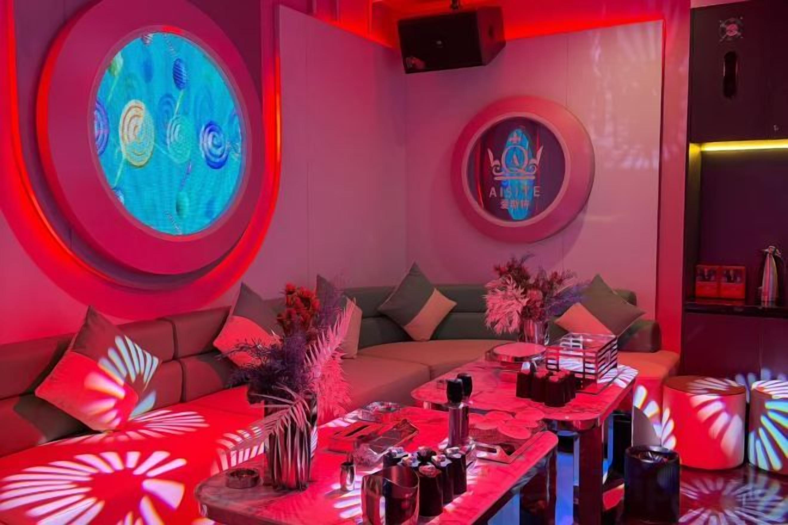 Uma área de estar moderna com decorações circulares nas paredes, um sofá e um bar com diversos objetos.
